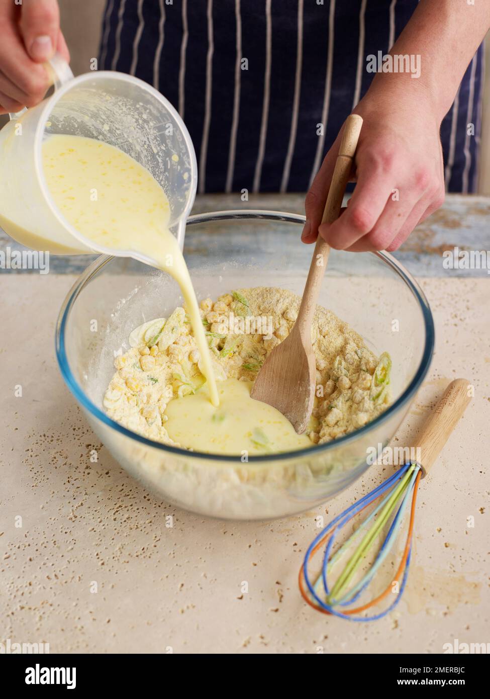 Corn bread, pouring egg and milk mixture into bowl containing corn ...