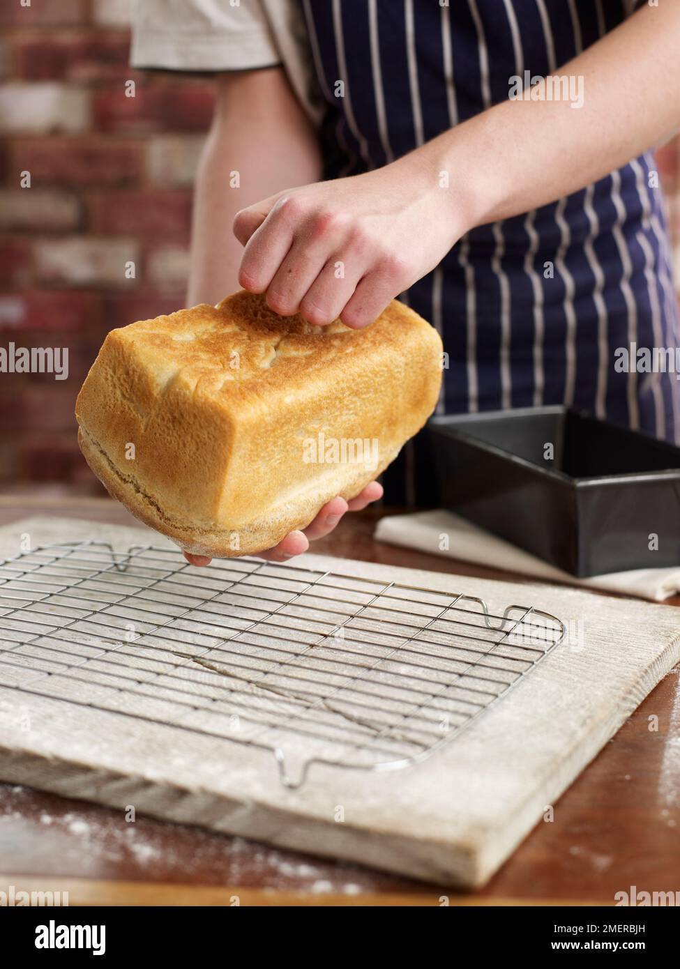 Making bread, tapping the bottom of baked loaf of bread to check if it ...