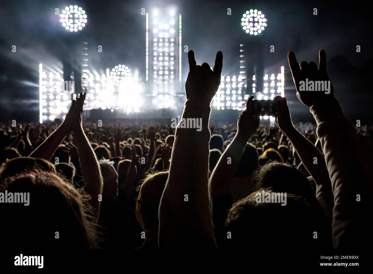 The happy crowd in a concert hall. Silhouettes of raised hands Stock ...