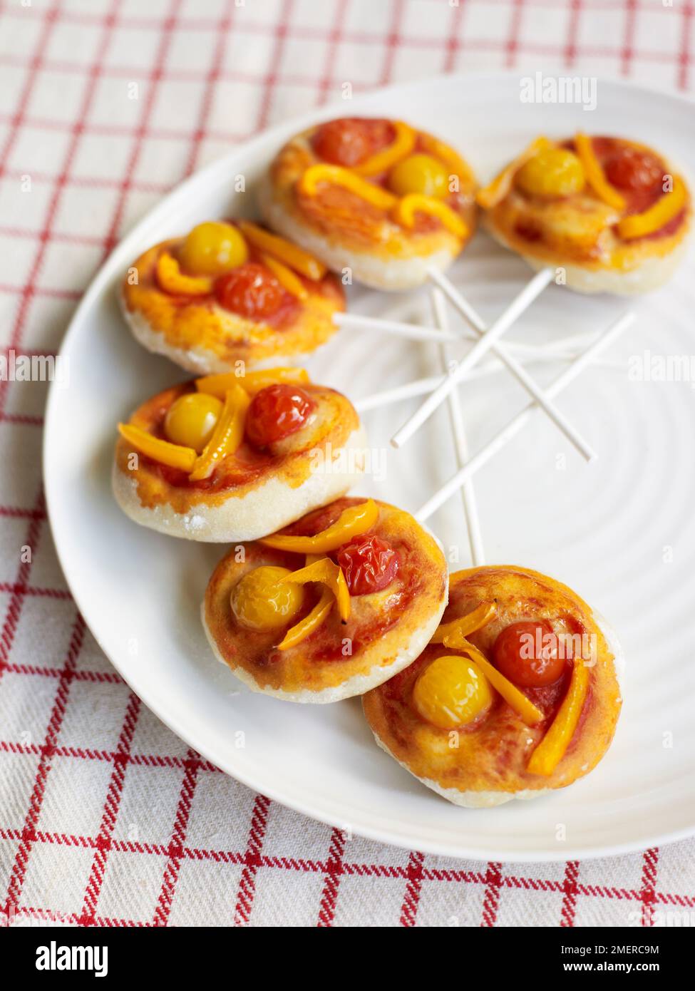 Lollipop style pizzas topped with cherry tomatoes and peppers, finger ...