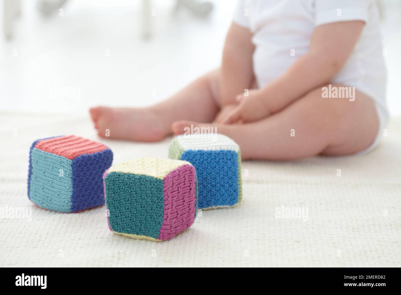 Knitted building blocks, baby boy sitting in background, 10 months ...