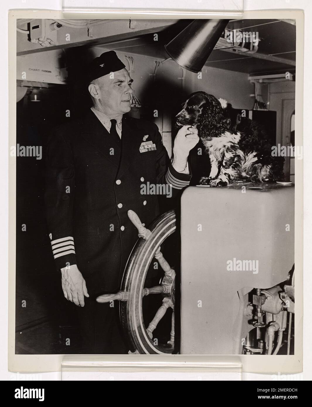 A black-and-white cocker spaniel sits beside Coast Guard Captain Carl C ...