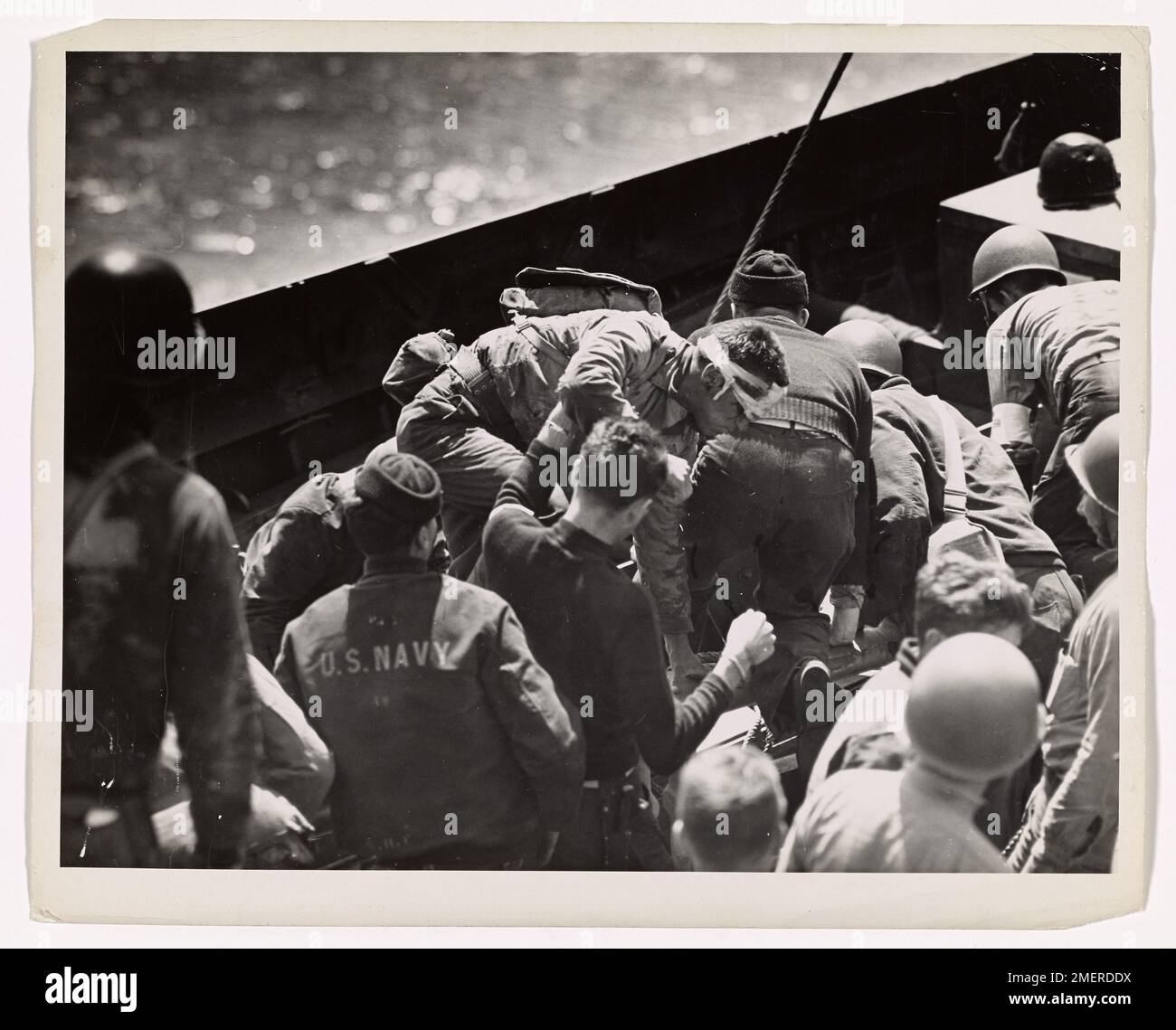 This image shows Coast Guardsmen assisting wounded soldiers from a ...