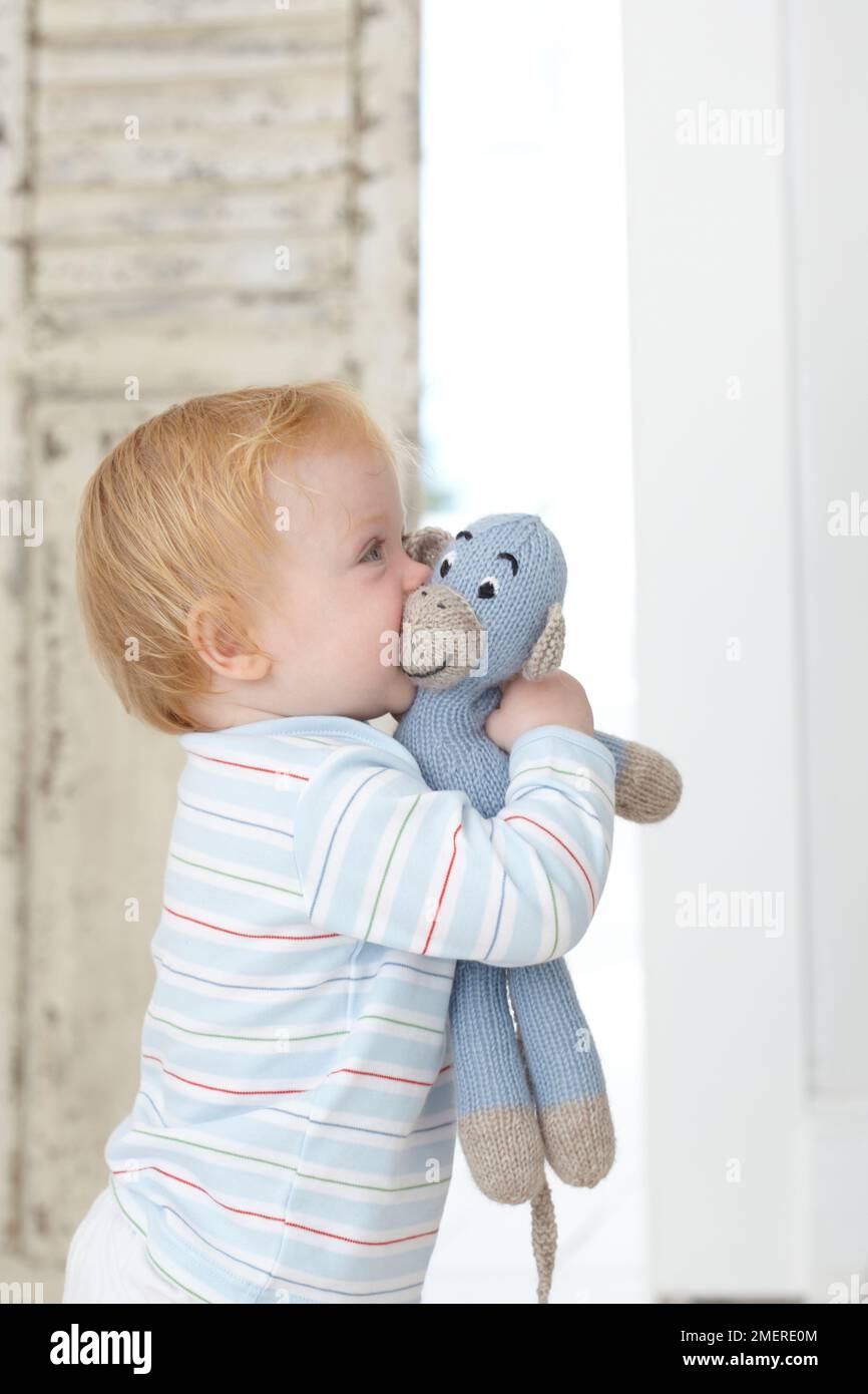 Baby boy hugging knitted monkey toy, 12 months Stock Photo - Alamy