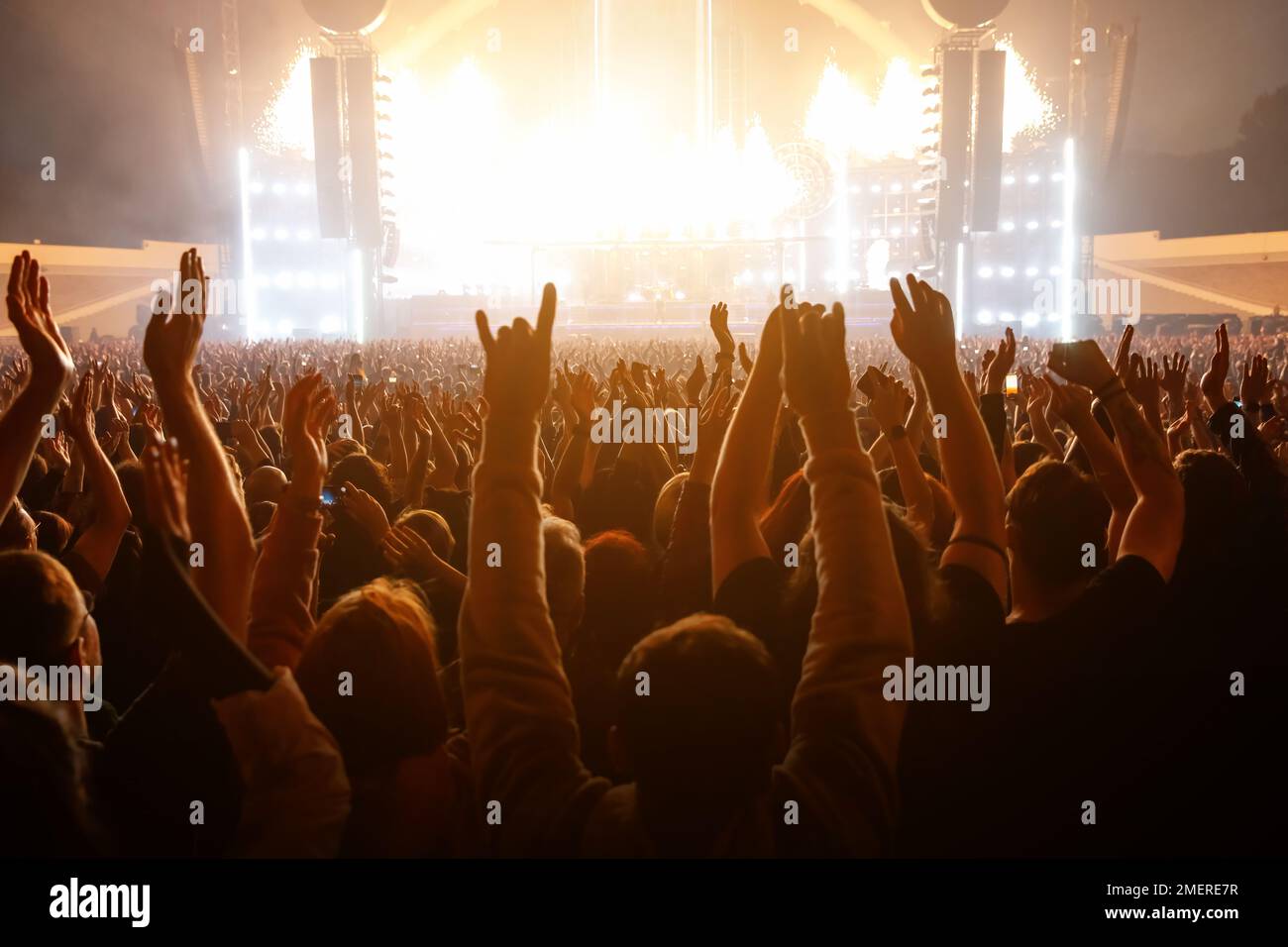 A crowd of people with raised arms during a music concert with an ...