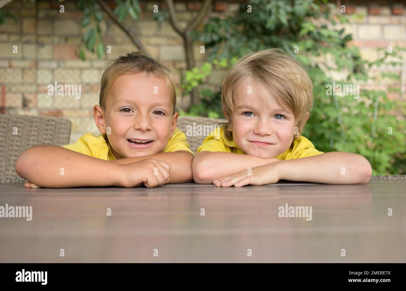 portrait of two similar cute smiling boys 5 years old in yellow t ...