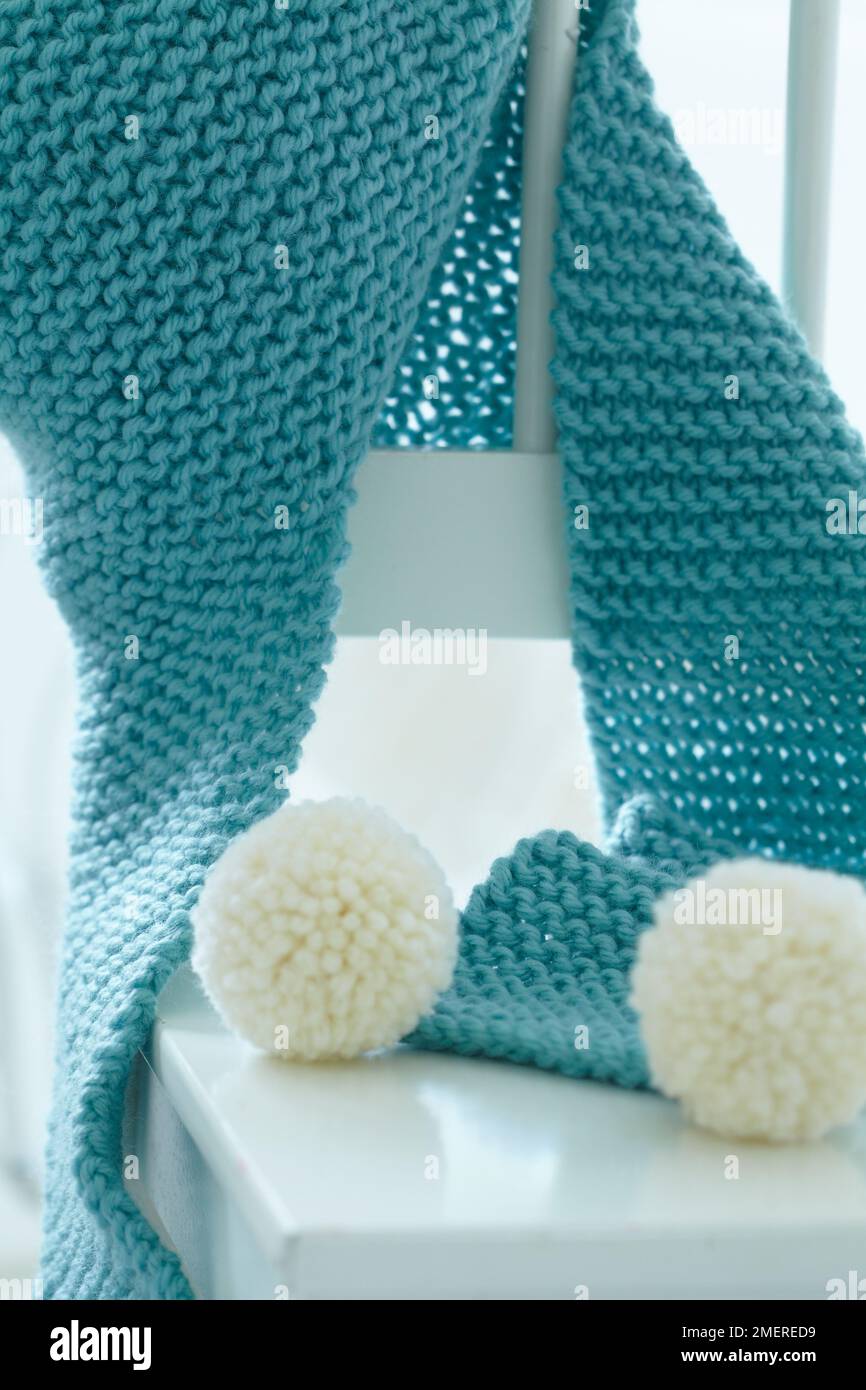 Knitted scarf hat draped over a child's wooden chair Stock Photo - Alamy