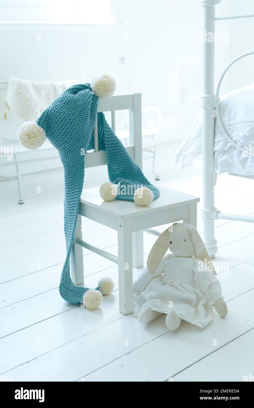 Knitted scarf hat draped over a child's wooden chair Stock Photo - Alamy