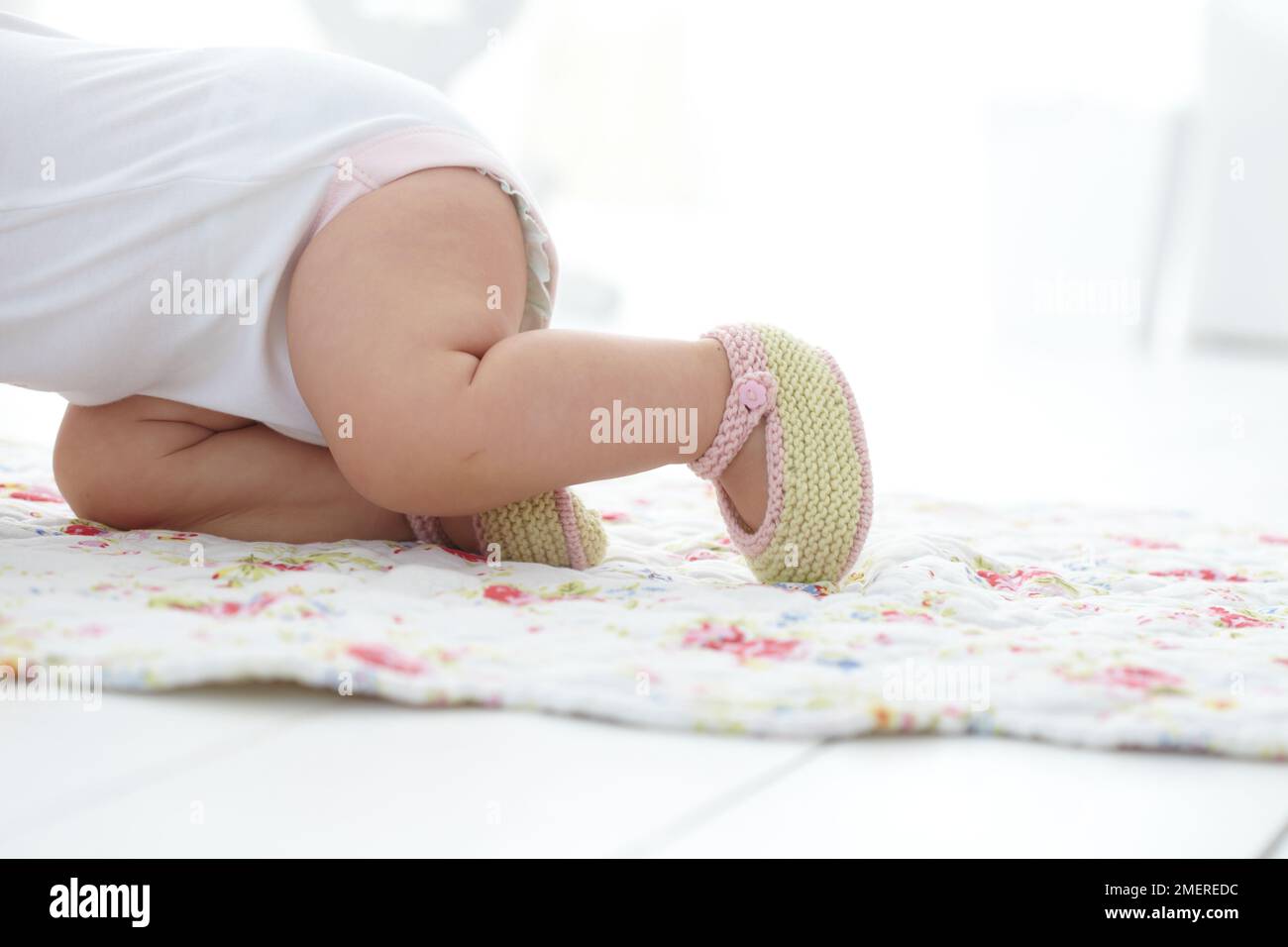 Baby girl crawling wearing knitted booties, 9 months Stock Photo - Alamy