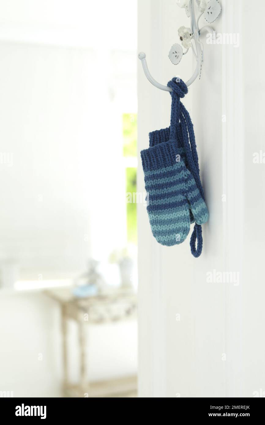Knitted striped mittens hanging from hook on back of door Stock Photo ...