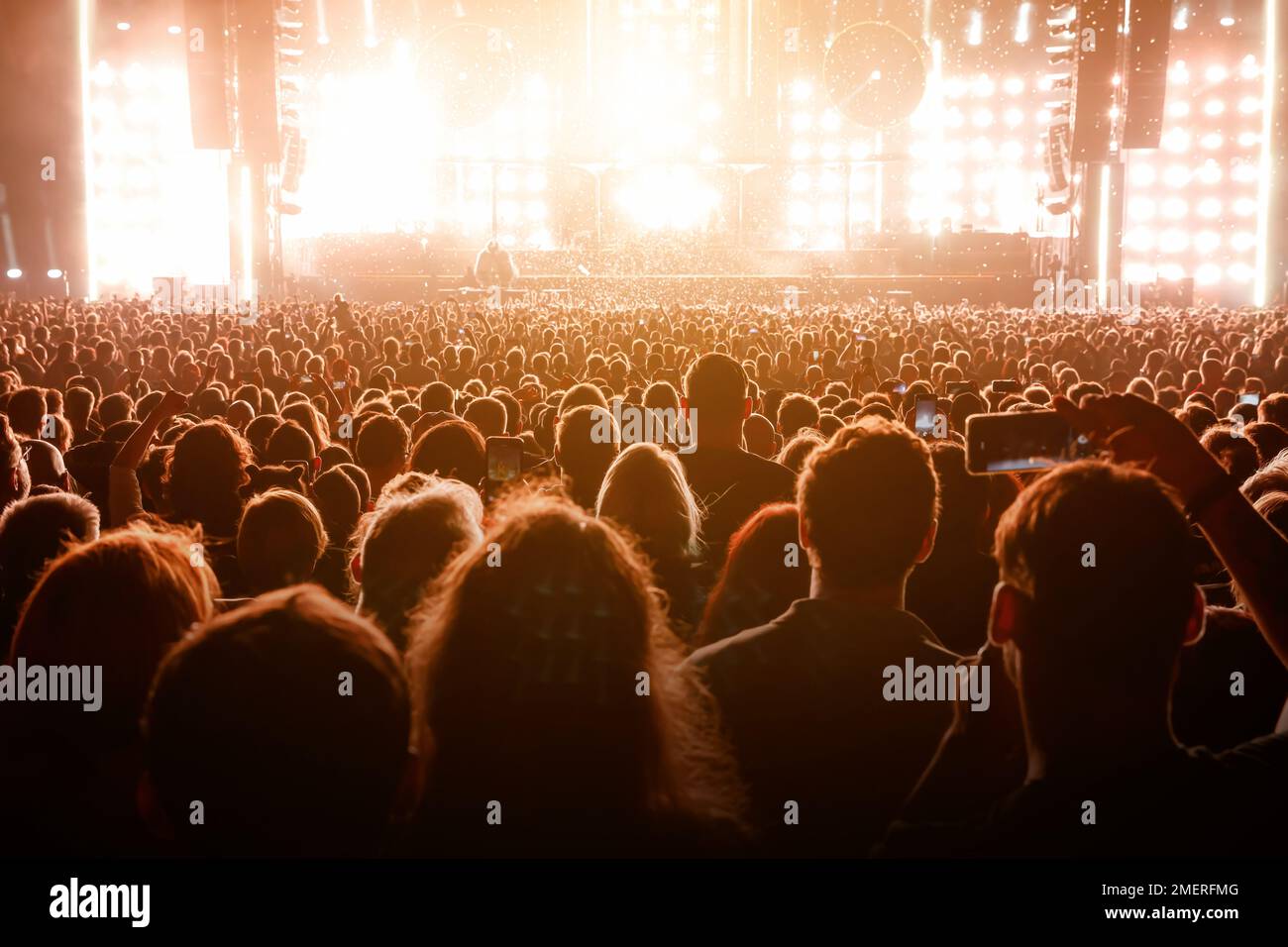 A crowd of people with raised arms during a music concert with an ...