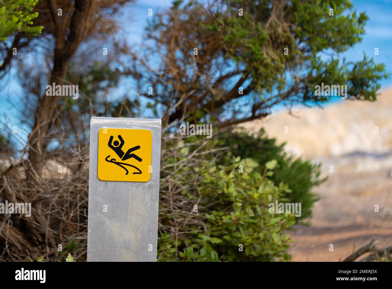 yellow warning sign with graphic of person slipping down an incline in ...