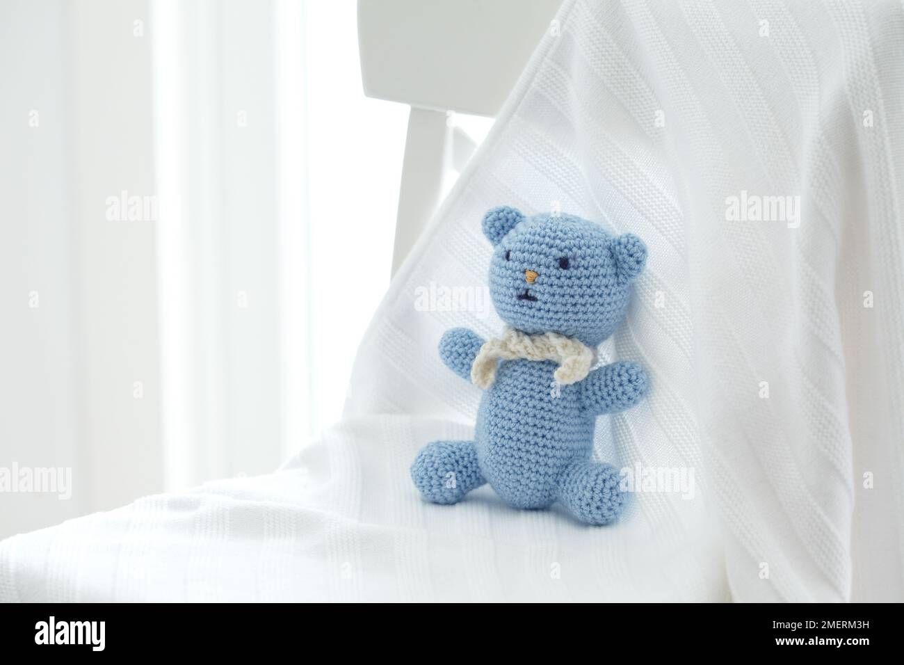 Crocheted blue teddy on chair Stock Photo - Alamy