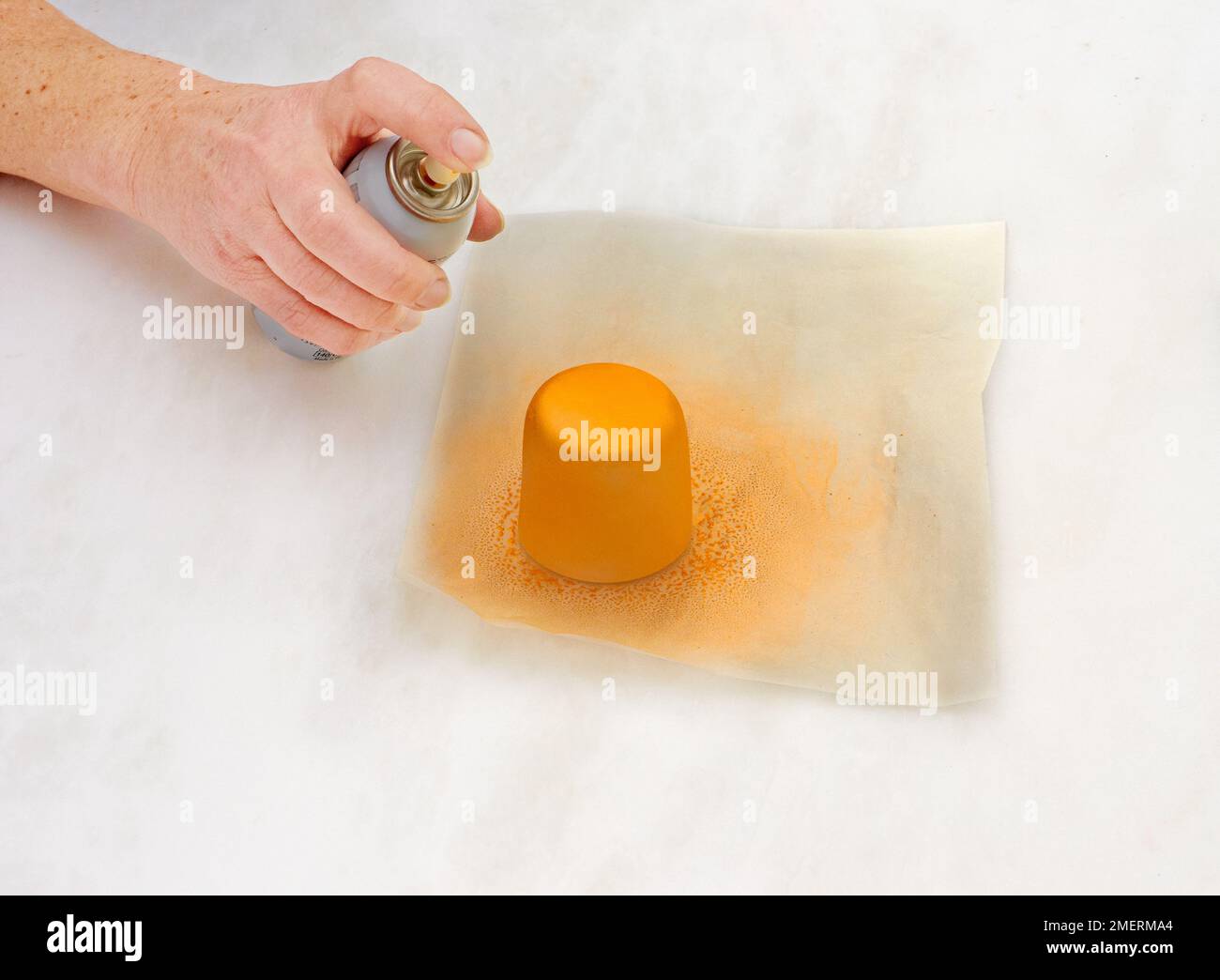 Spraying yellow food colour on small cakes covered with icing Stock ...
