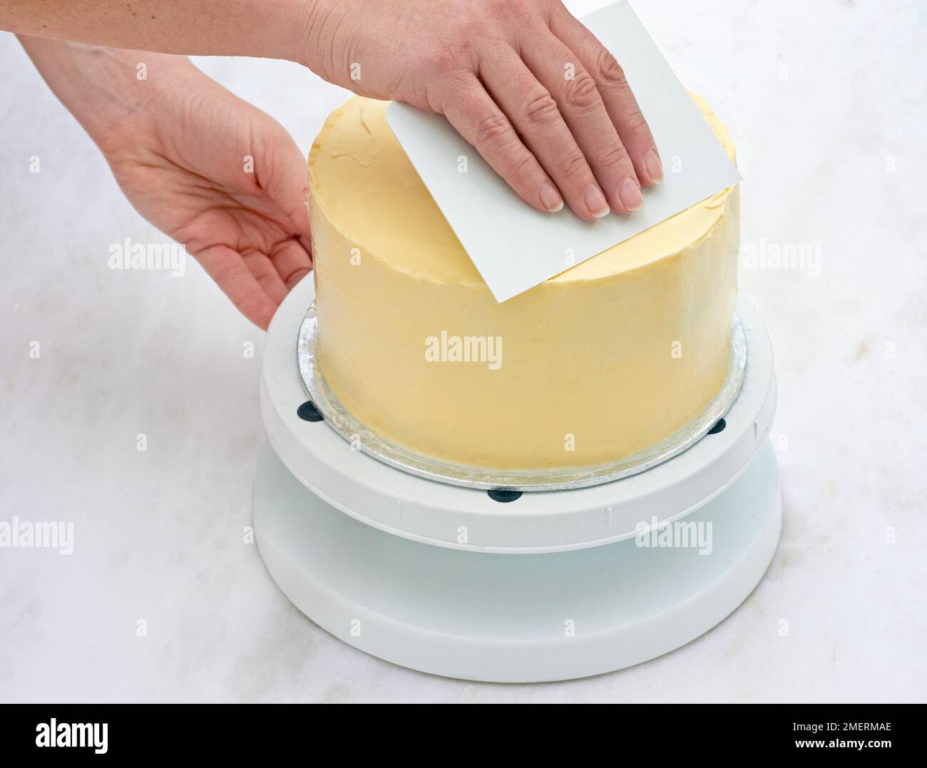 Smoothing buttercream icing on cake Stock Photo - Alamy