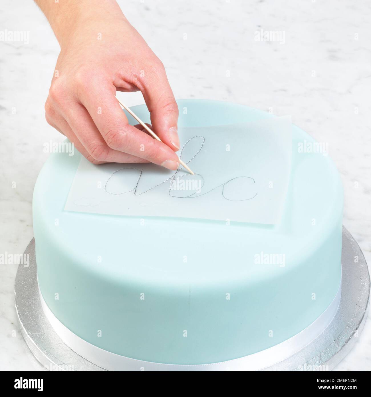 Scoring letters on top a smooth iced cake using cocktail stick Stock ...