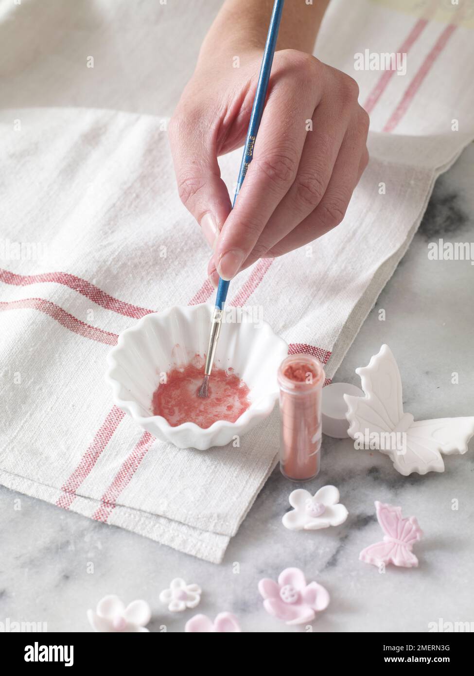 Flowers and butterflies made of icing being painted using food ...