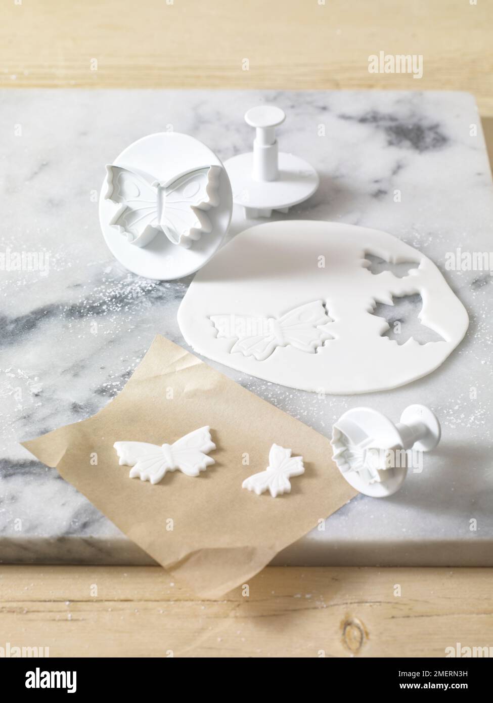 Butterflies being cut from icing sugar using shaped cutters and placed ...