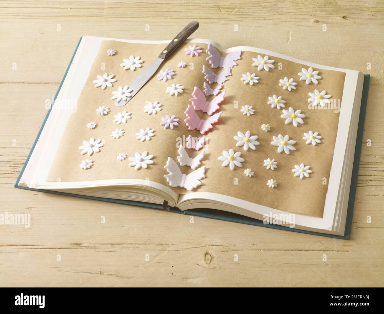 Open book with parchment and spatula, icing flowers and butterflies ...