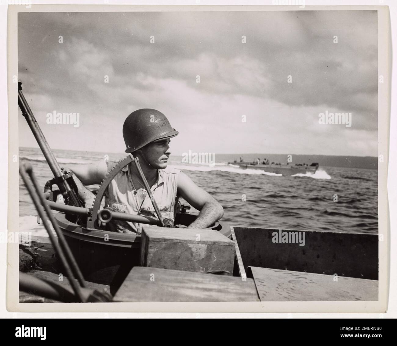Coast Guardsman Deno Kostakis mans a gun aboard a landing craft in the ...
