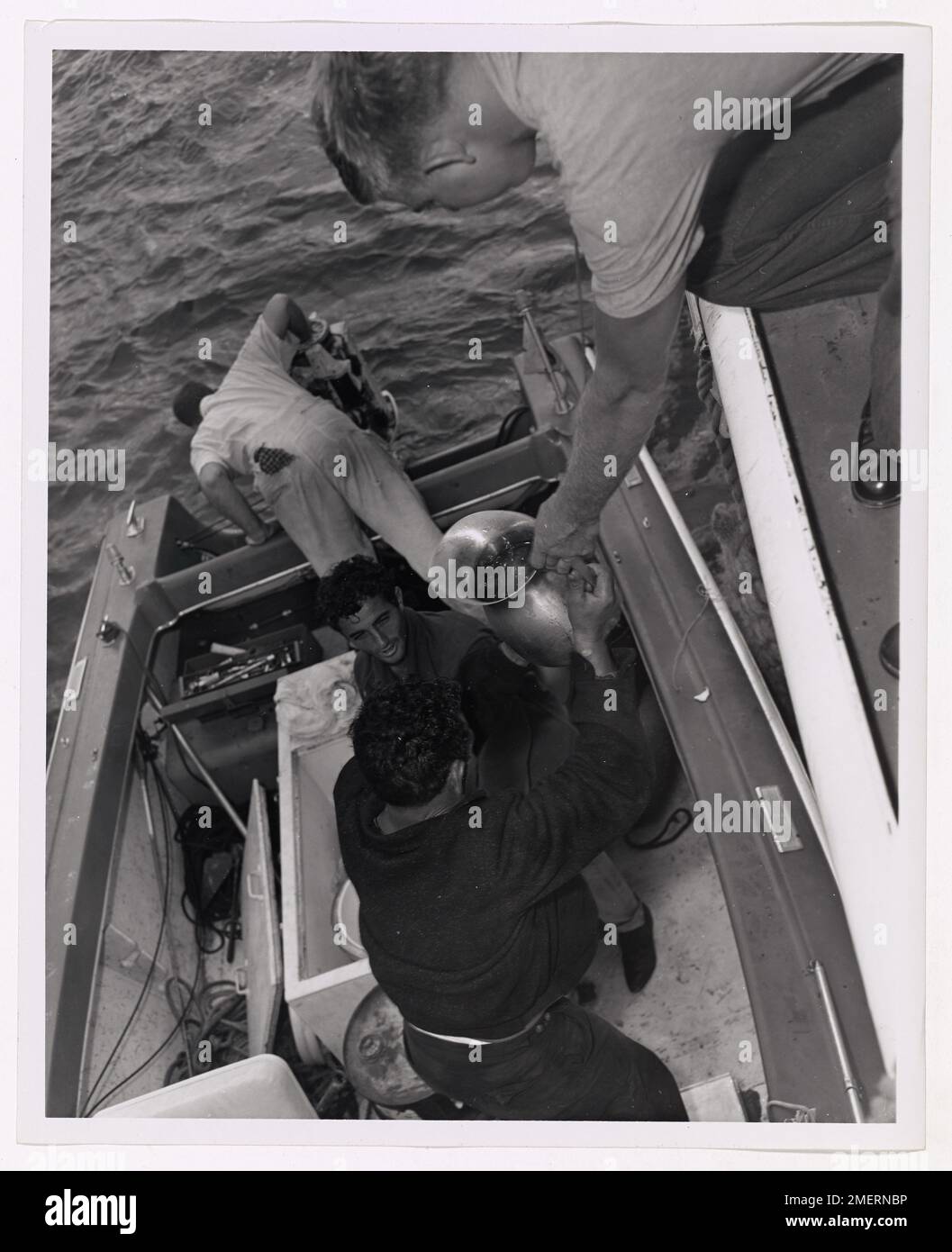A photograph shows fresh water being handed down from the cook aboard ...