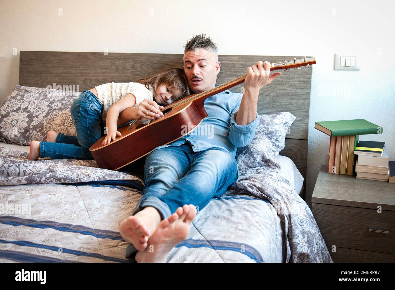Cool daddy playing the acoustic guitar and teaching a song while his ...