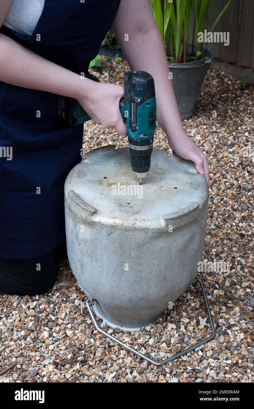 Drilling hole in bottom of milk churn container Stock Photo - Alamy