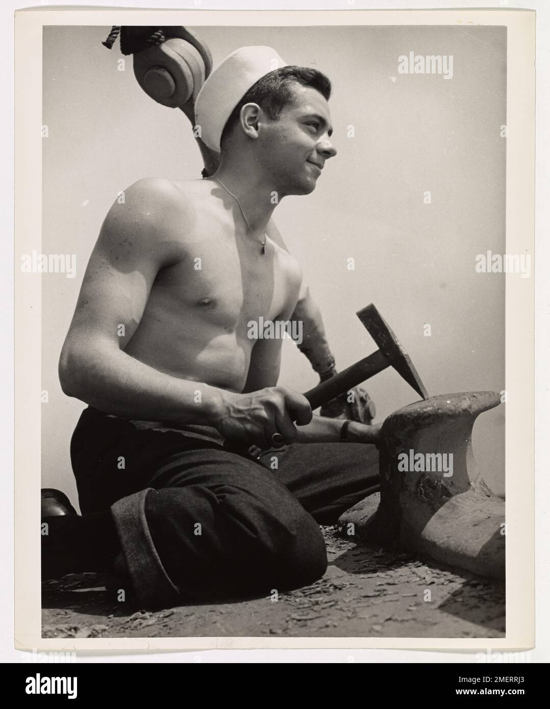 A U.S. Coast Guard sailor chips paint on a vessel as part of routine ...