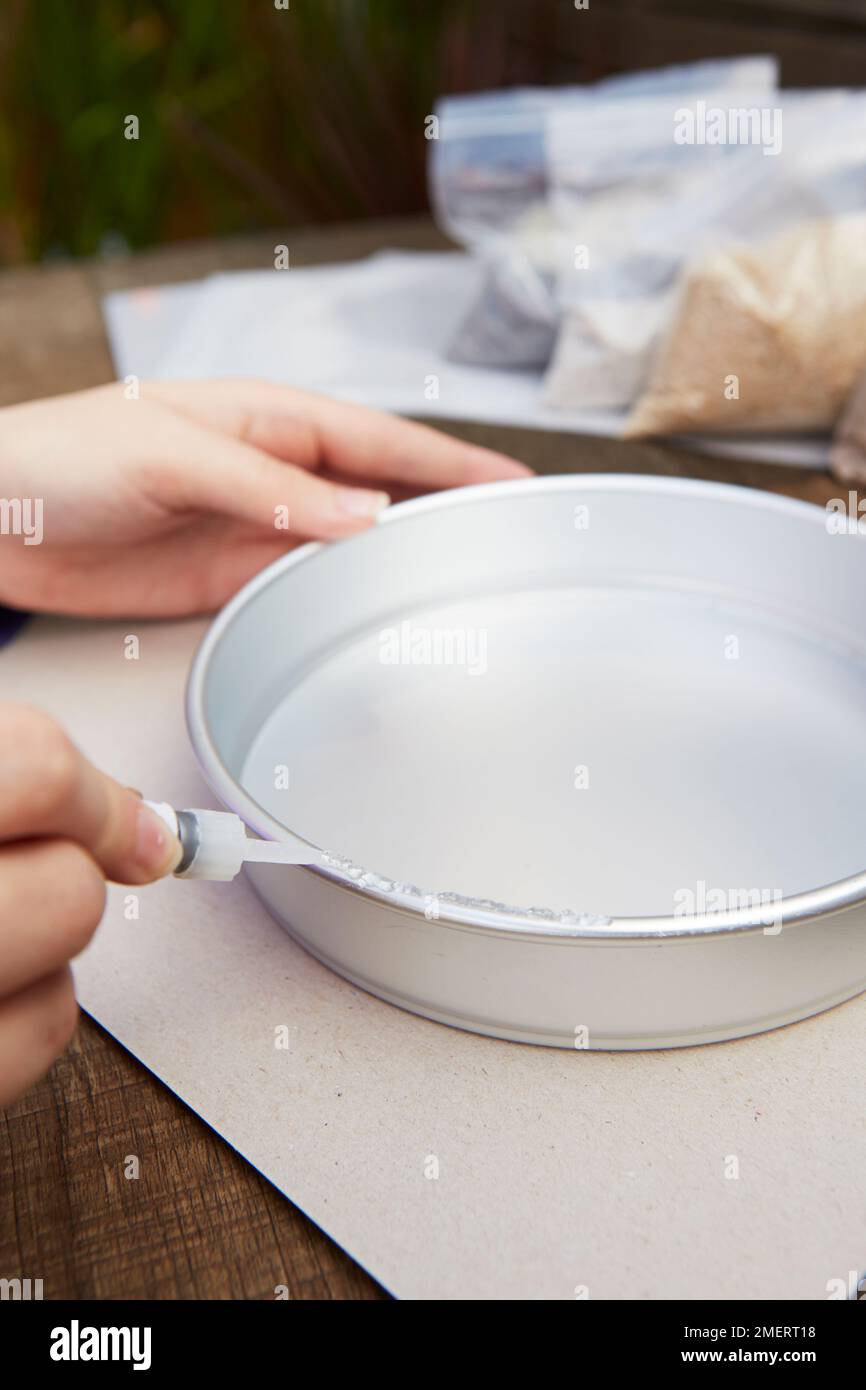 Applying superglue on edge of cake tin to make plant canister Stock ...