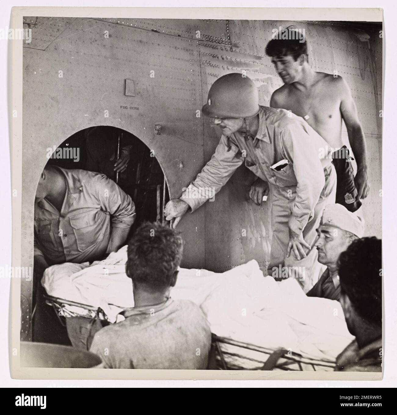 At Makin, Coast Guardsmen assist in lifting a wounded soldier onto a ...