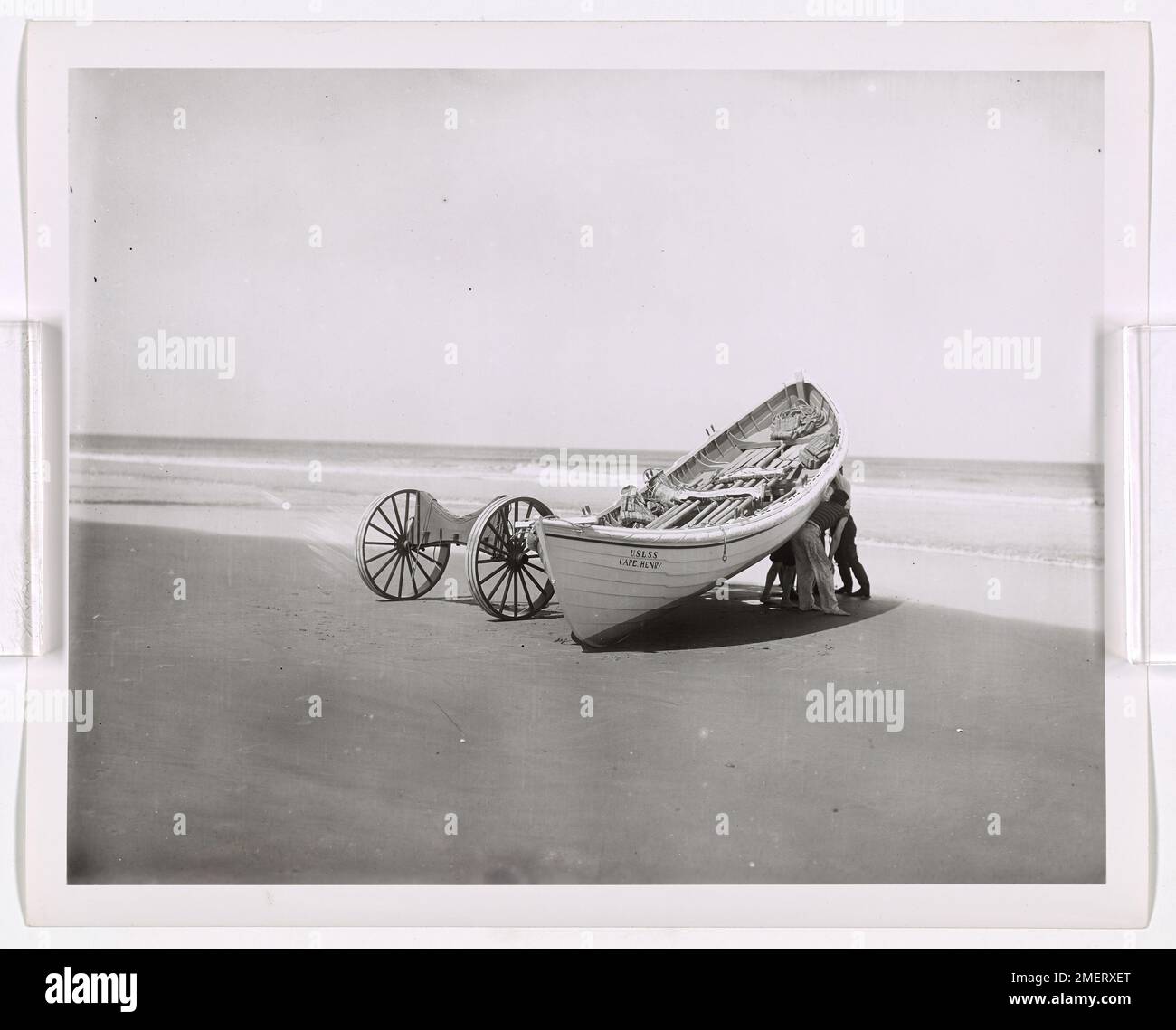 A group of Coast Guardsmen lift the USLSS Cape Henry, a small boat used ...