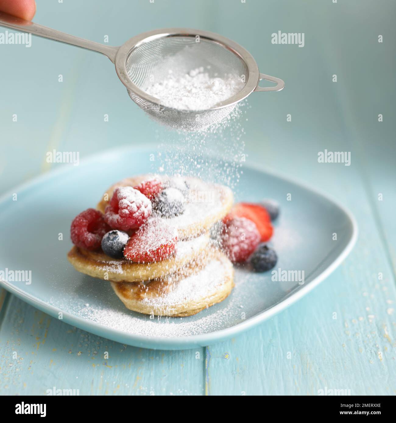 Sieving icing sugar on to fruit and pancakes Stock Photo - Alamy