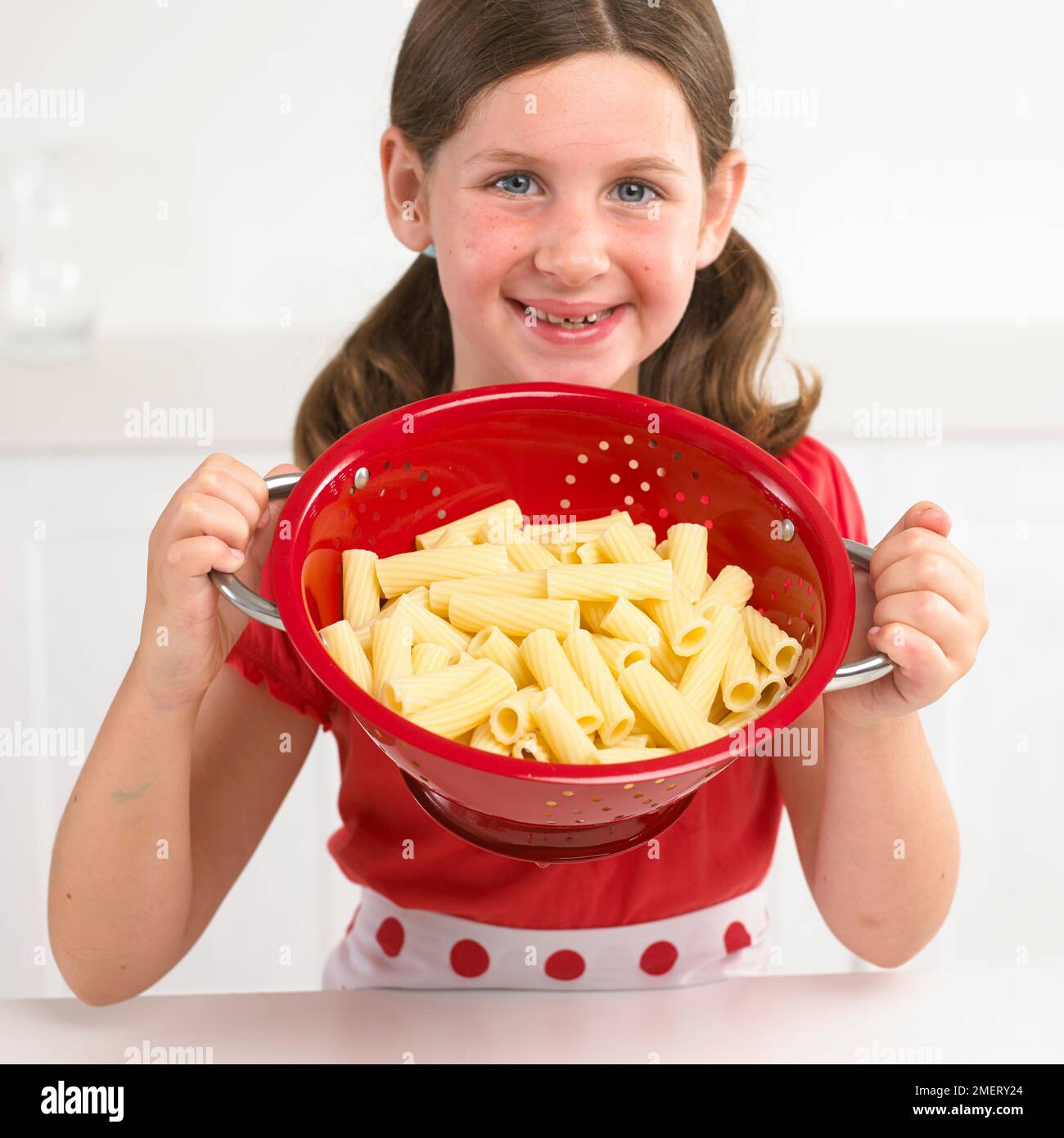 Girl holding colander of cooked pasta, 7 years Stock Photo - Alamy