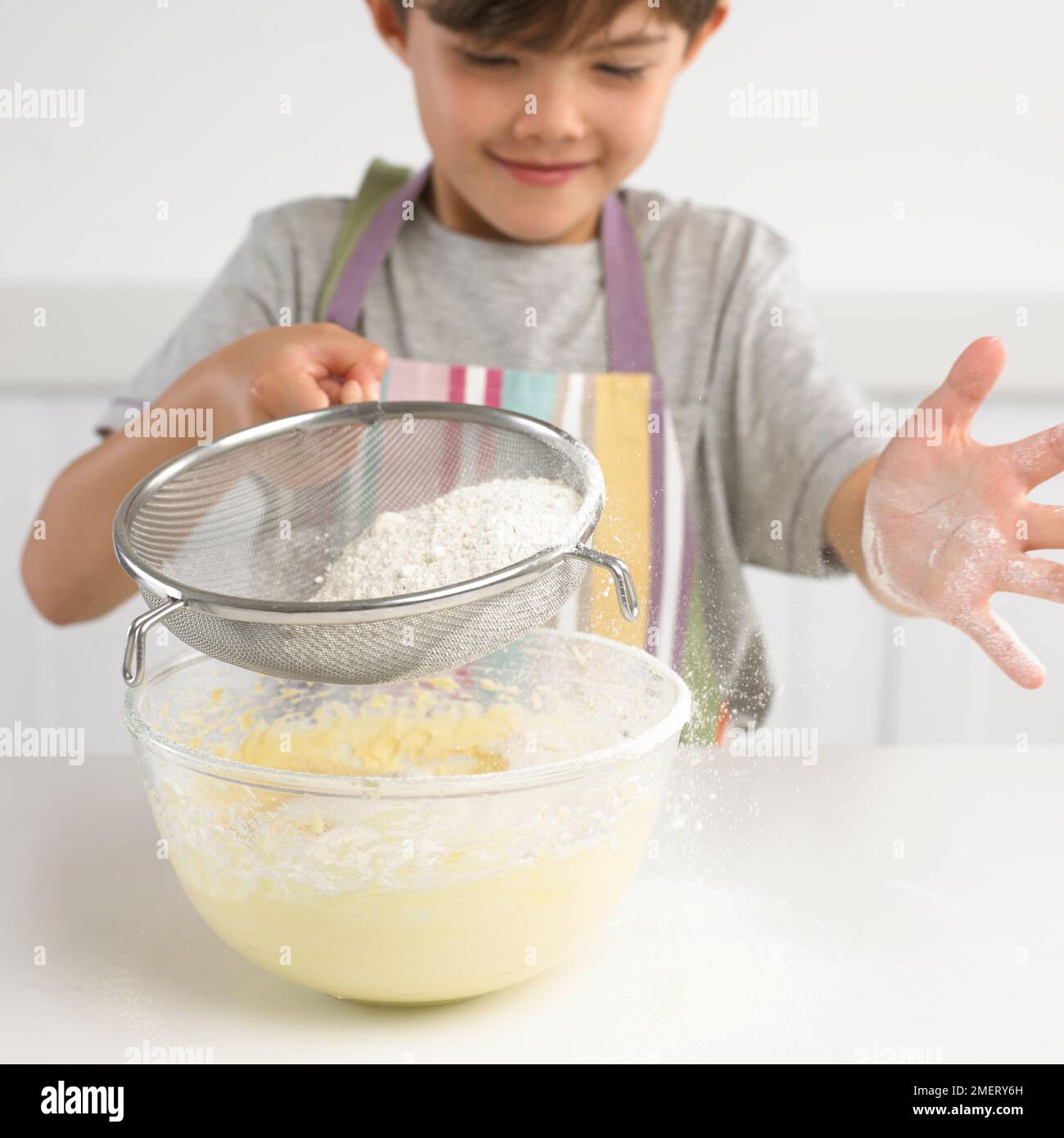 Boy sieving flour over a bowl of cake mixture, 7 years Stock Photo - Alamy
