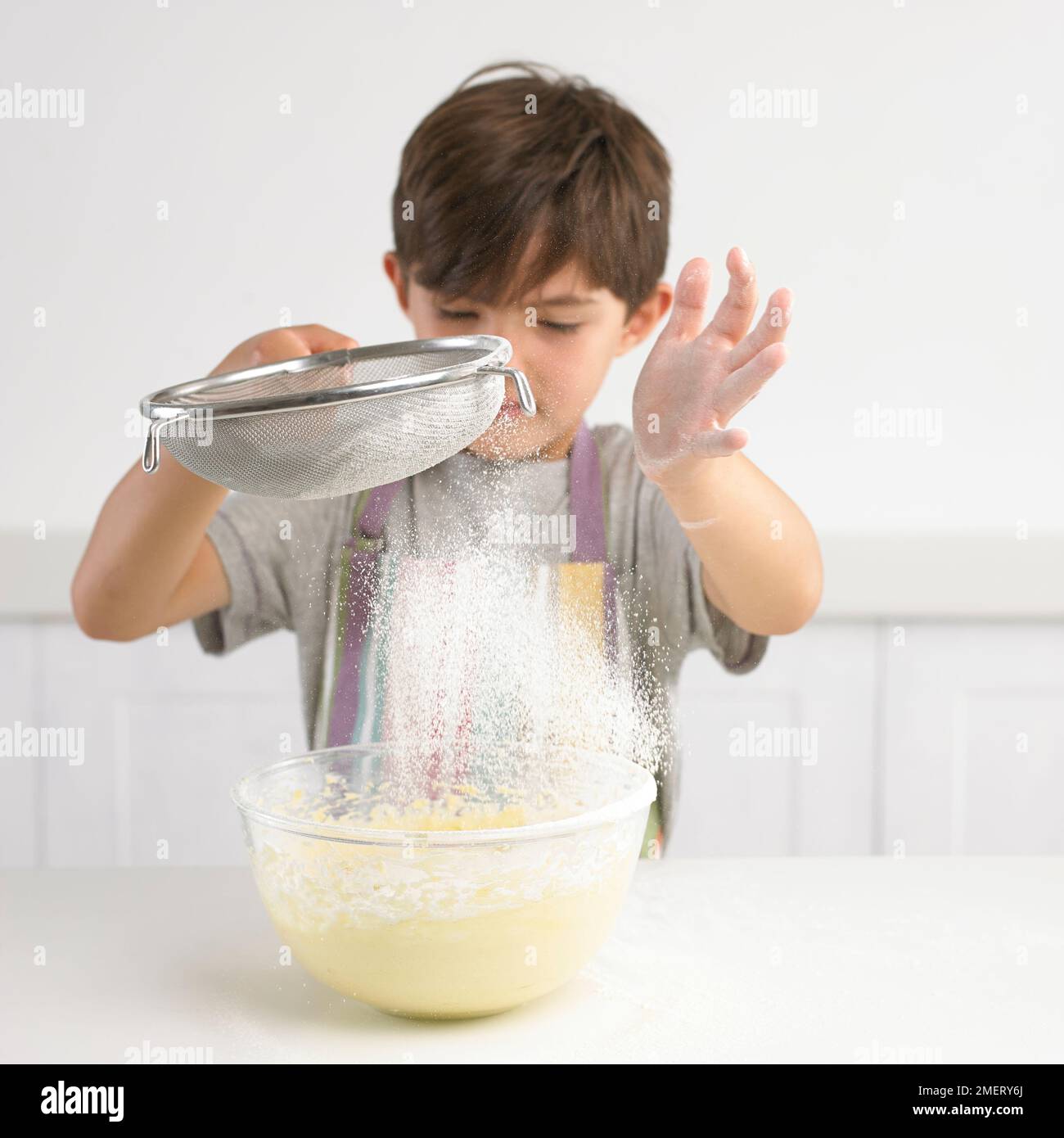 Boy sieving flour over a bowl of cake mixture, 7 years Stock Photo - Alamy