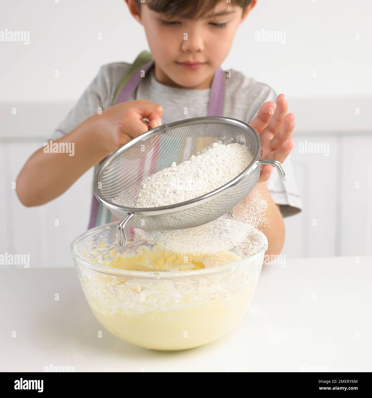 Boy sieving flour over a bowl of cake mixture, 7 years Stock Photo - Alamy