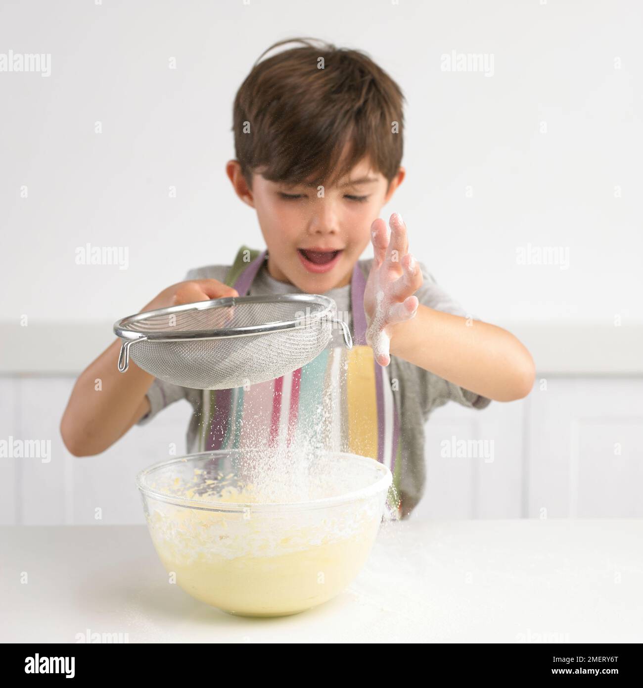 Boy sieving flour over a bowl of cake mixture, 7 years Stock Photo - Alamy
