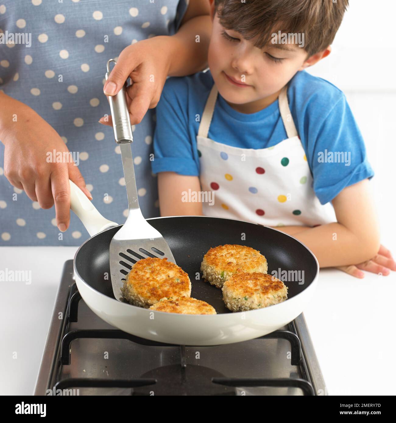 Boy frying two fishcakes and salad, 7 years Stock Photo - Alamy