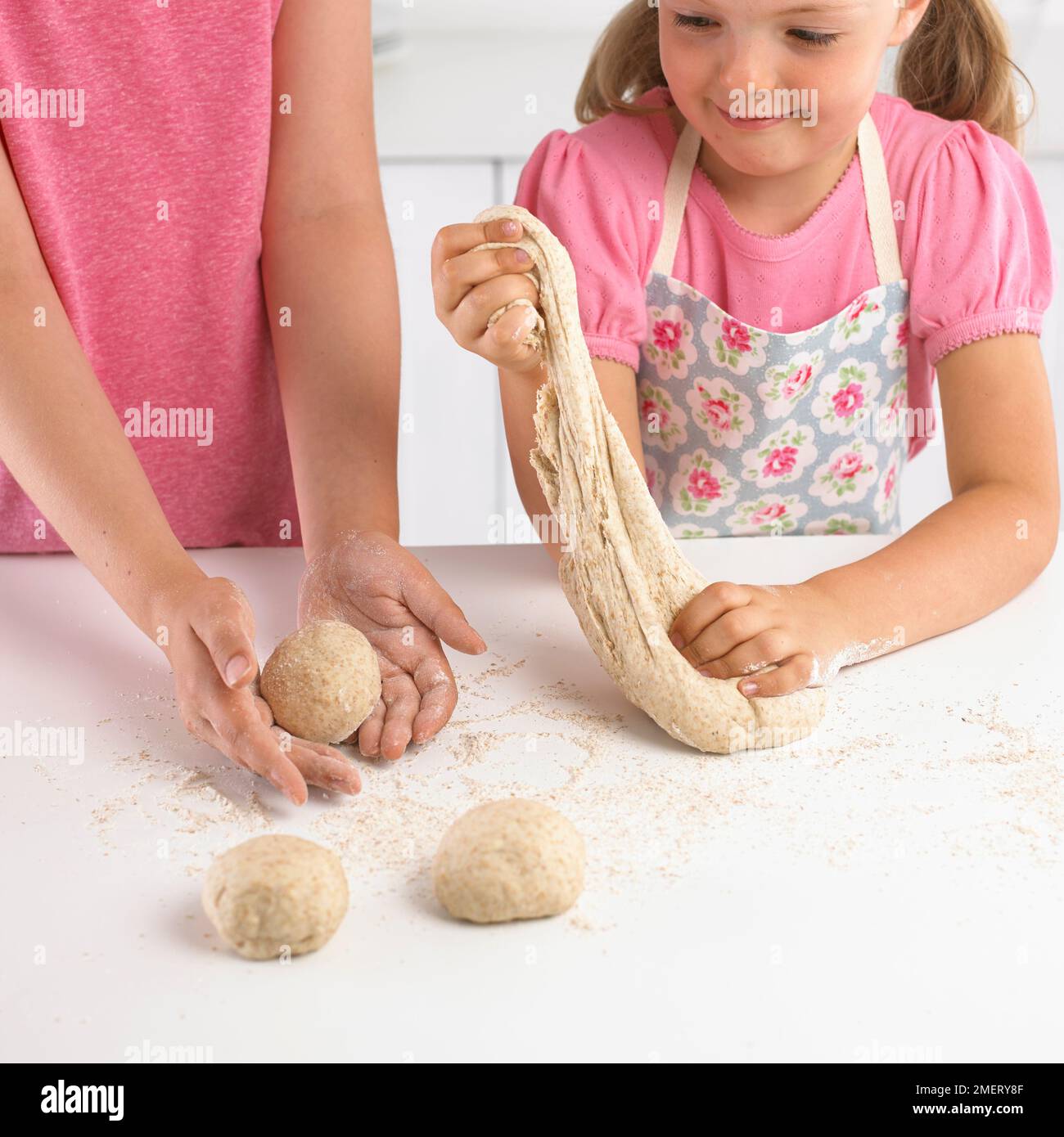 Girl breaking off pieces of dough to make bread rolls, 5 years Stock ...