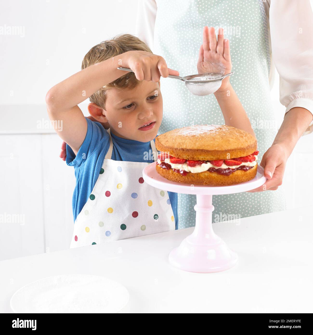 Boy sieving icing sugar onto strawberry sponge, 6 years Stock Photo - Alamy