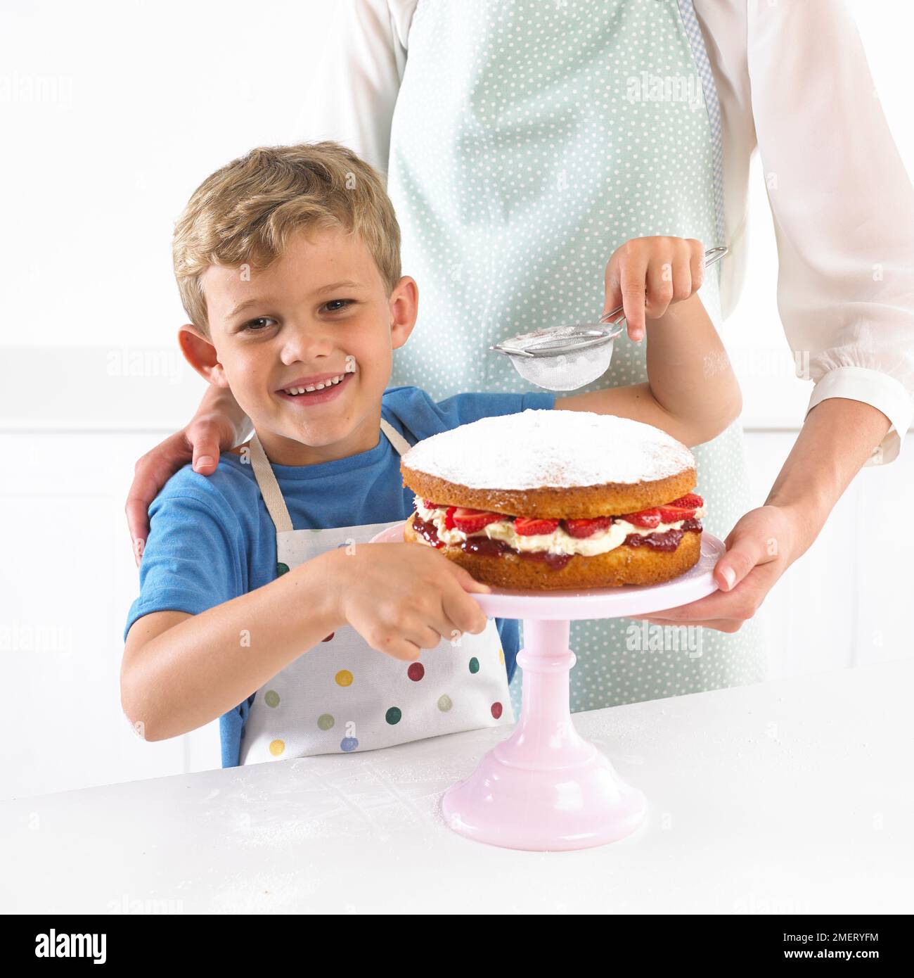 Boy sieving icing sugar onto strawberry sponge, 6 years Stock Photo - Alamy