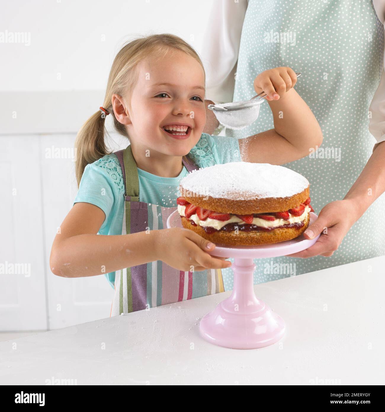 Girl sieving icing sugar on a strawberry sponge, 5 years Stock Photo ...