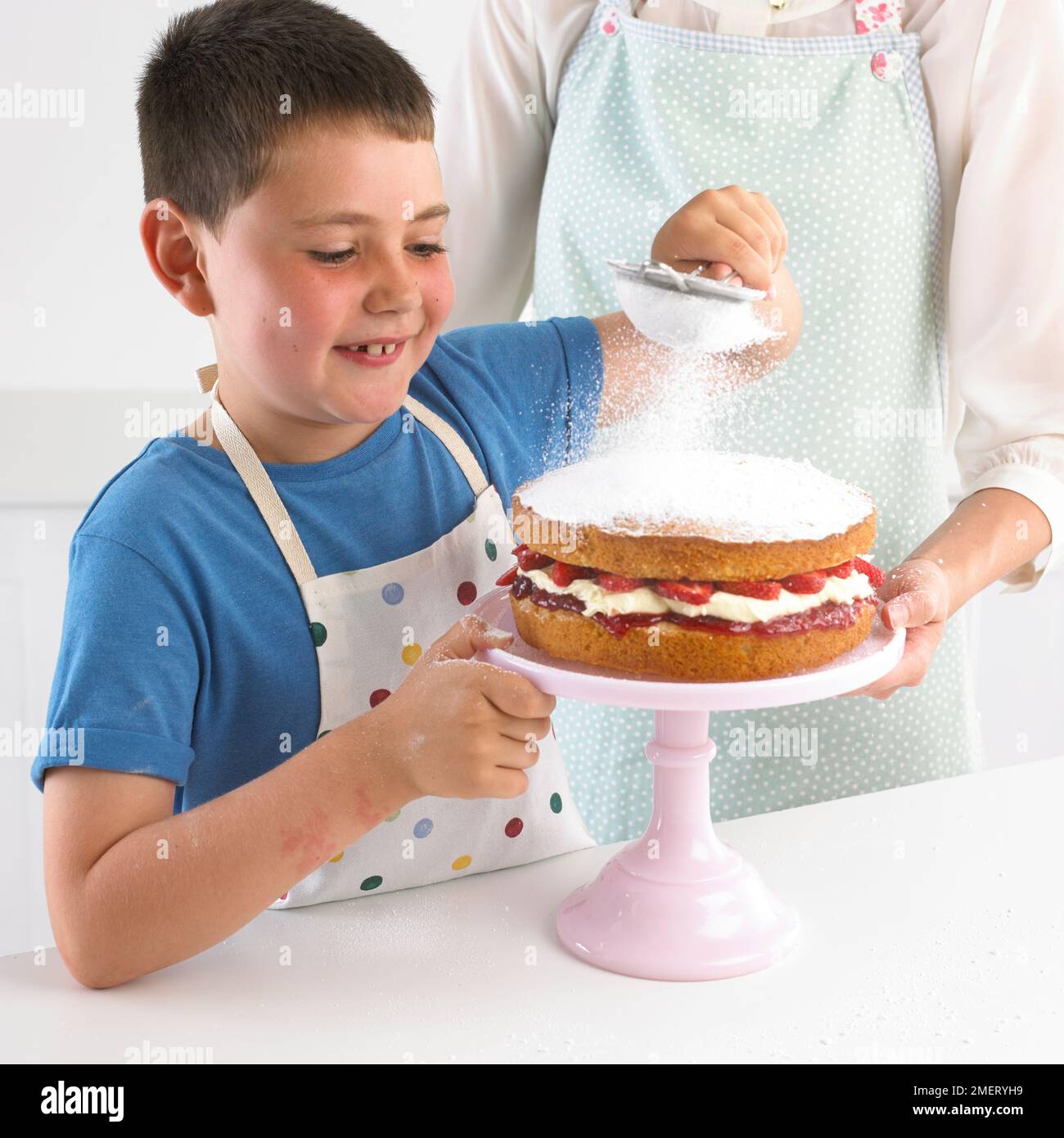 Sieving icing sugar over strawberry sponge cake, 7 years Stock Photo ...
