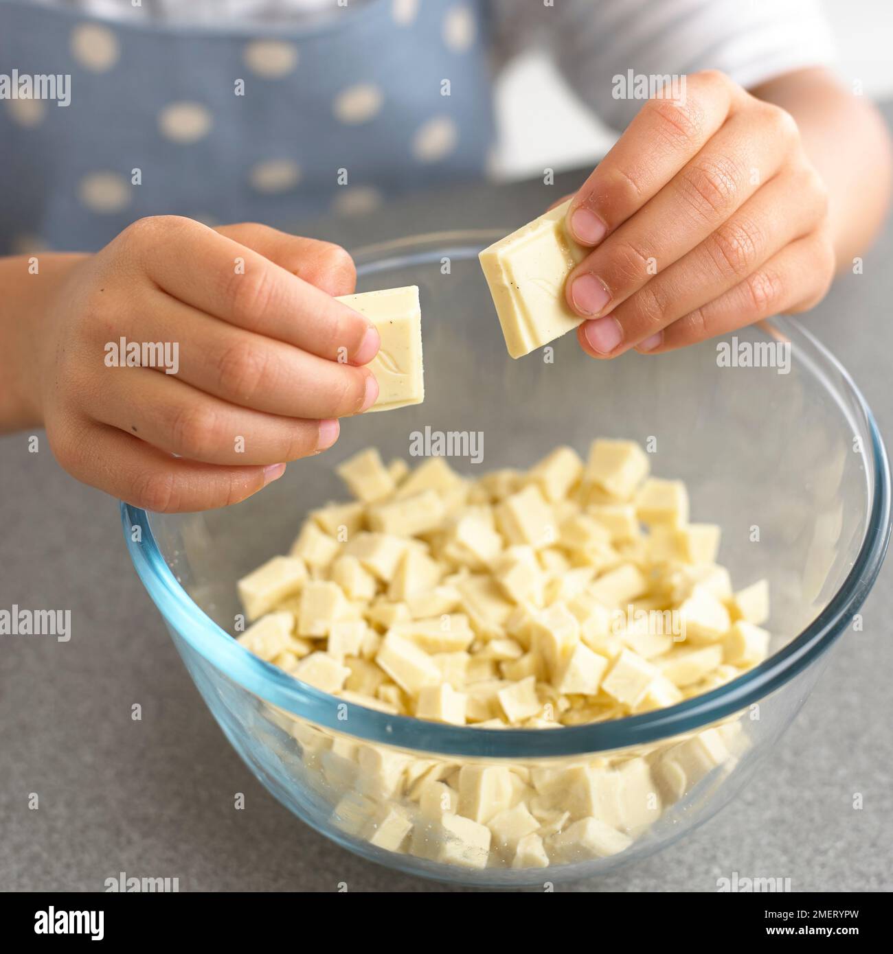 Breaking pieces of white chocolate into a bowl Stock Photo - Alamy