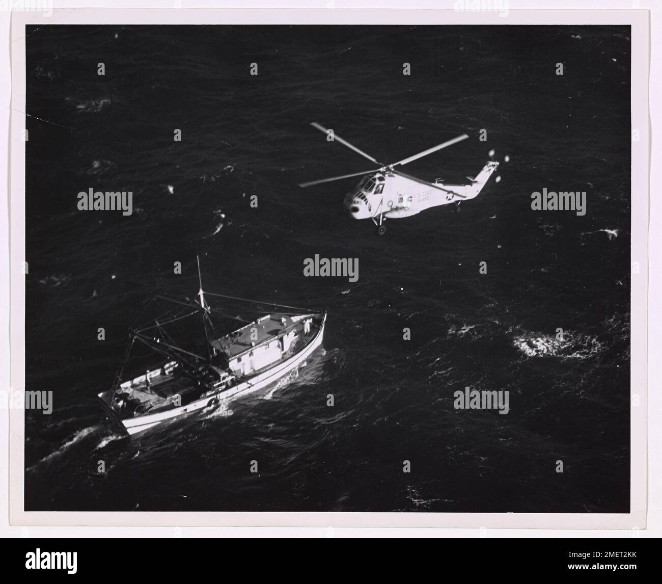 A Coast Guard helicopter provides aid to the sinking fishing vessel ...