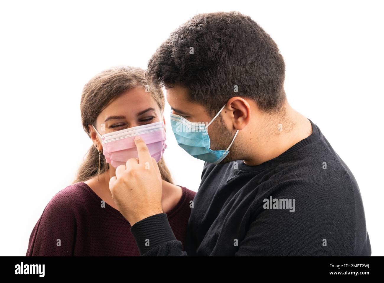 Cute man wearing blue protective face covering touching girlfriend nose ...