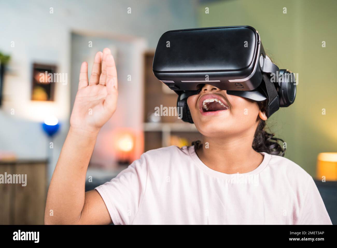 Smiling teenger girl kid with VR or virtual reality headset saying hi ...