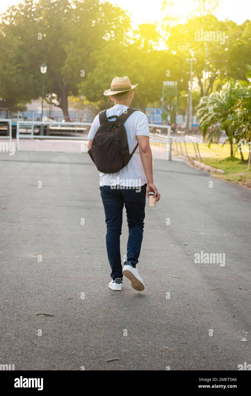 Man walking on street with backpack, from behind Stock Photo - Alamy