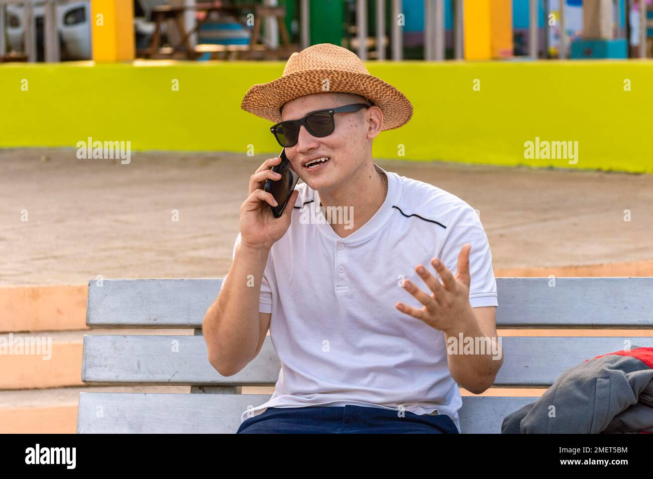 An attractive guy calling on a cell phone on a bench, a man sitting on ...