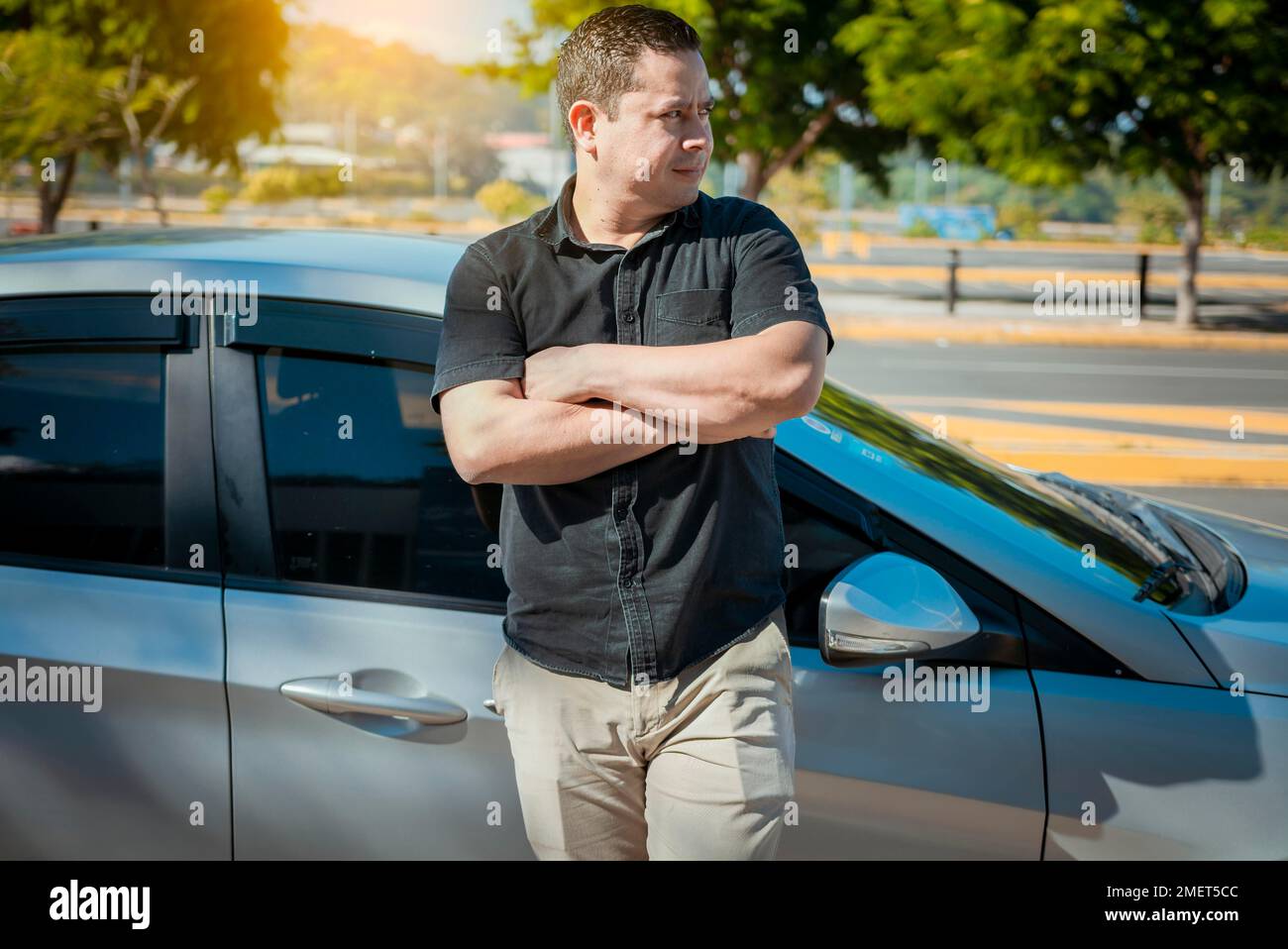 Man with crossed arms leaning on the car. Young man with arms crossed ...
